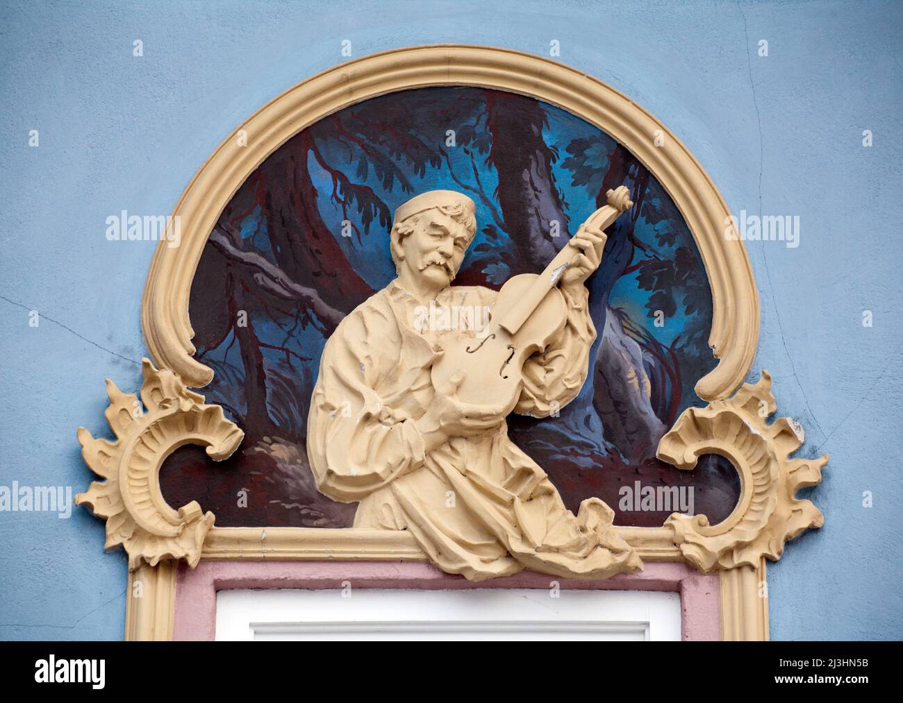 framed stucco figure of a violin maker on house facade in Mittenwald ...