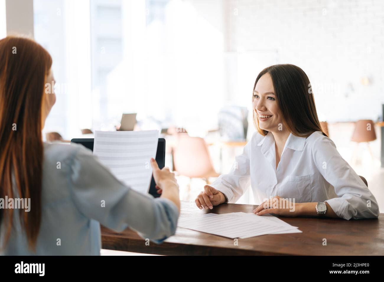 Two young businesswomen discussing new project sharing ideas sitting at ...