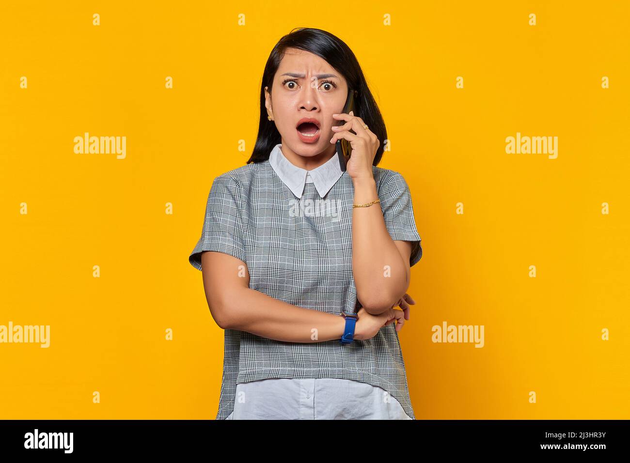 Portrait of shocked young Asian woman while receiving incoming call on ...
