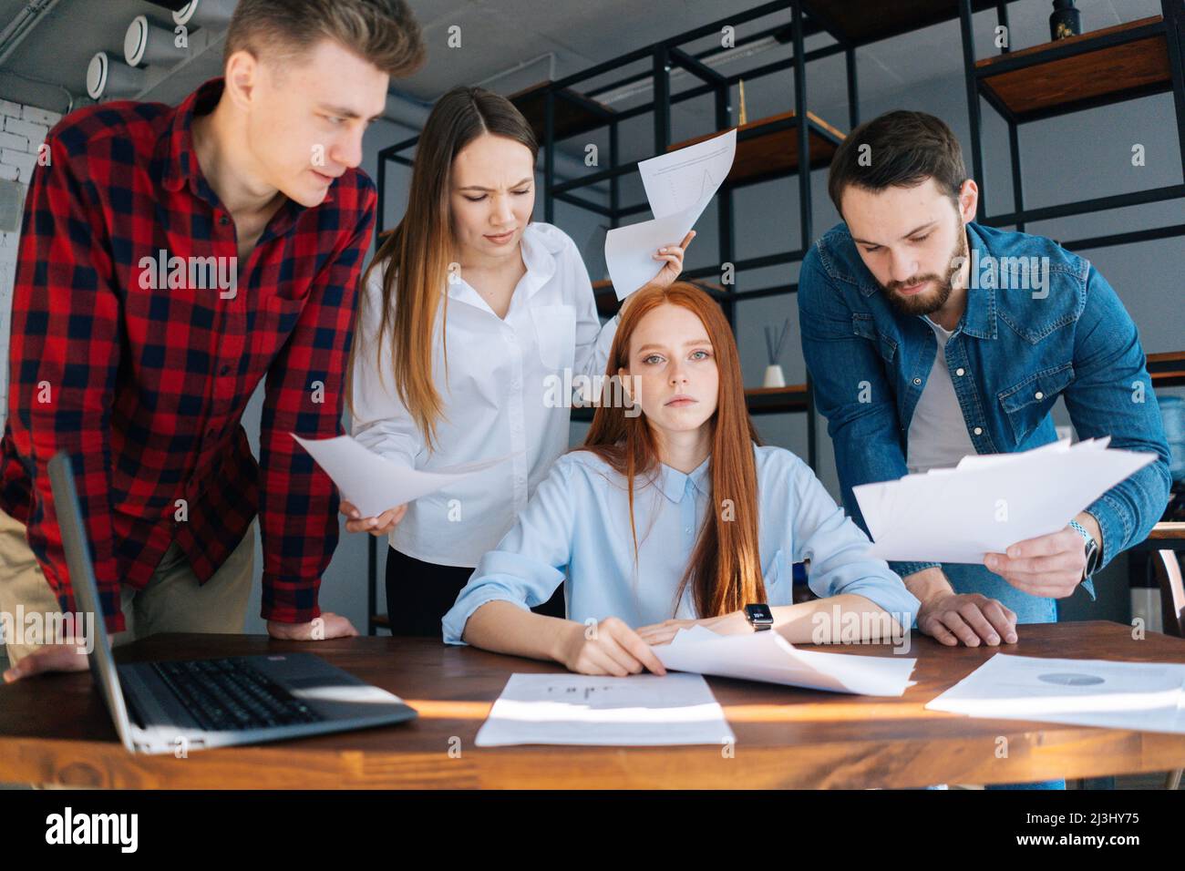 Tired young female team leader under stress at office sitting at desk ...