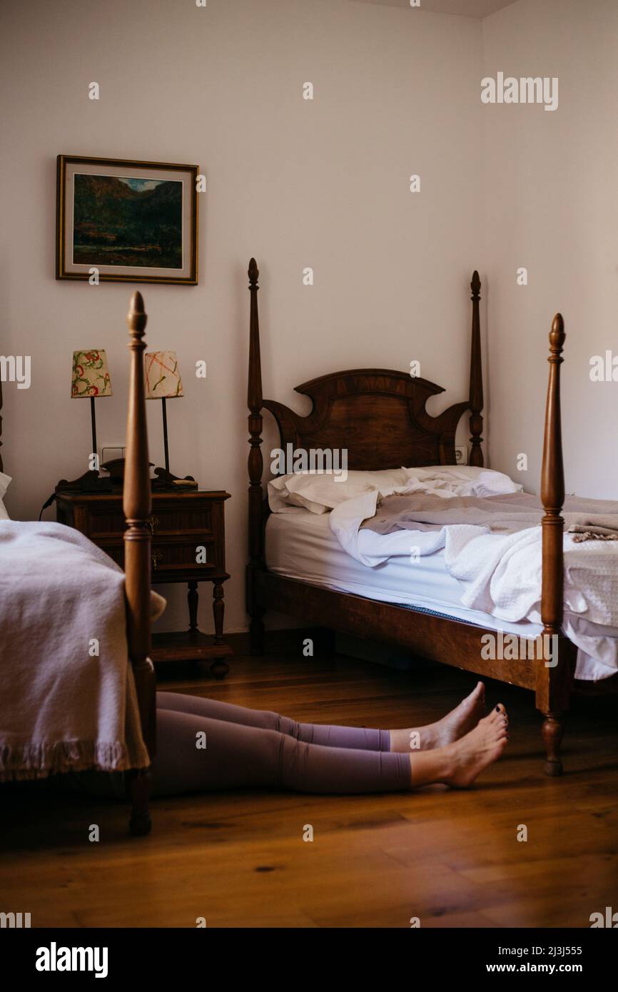 Woman lying half under a bed in a small bedroom hi-res stock ...