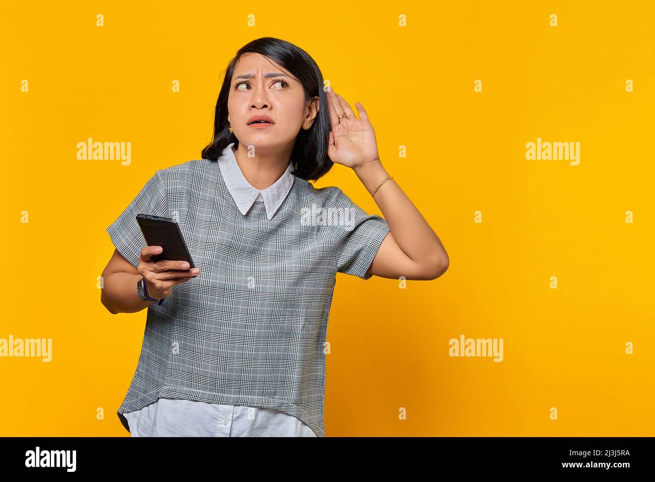 Portrait of serious looking asian woman trying to overhear secret ...