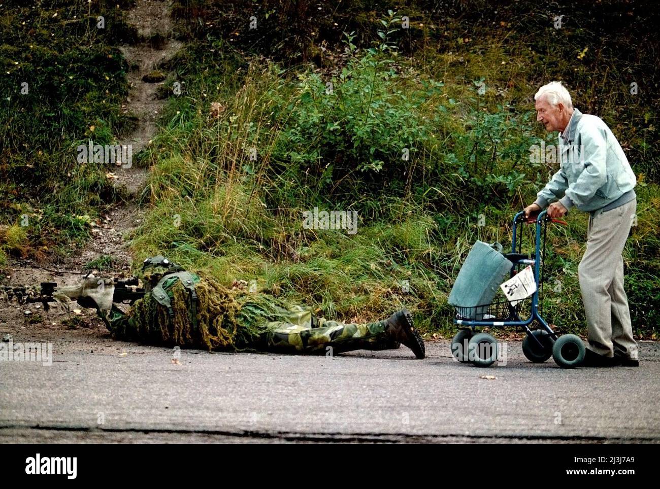 Camouflaged military soldiers on military training. A man with a walker ...