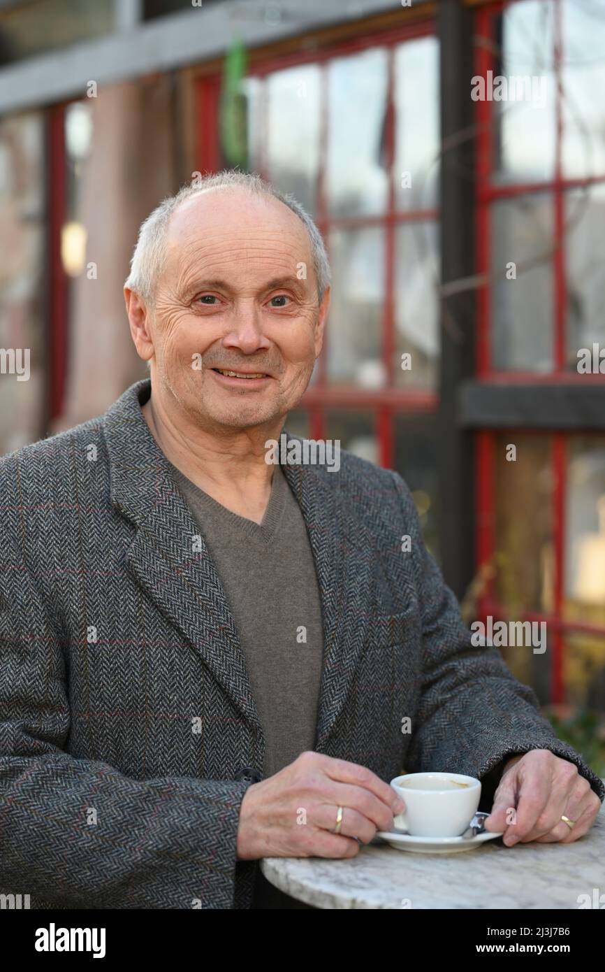 Portrait of smiling gray haired man standing in garden drinking coffee ...