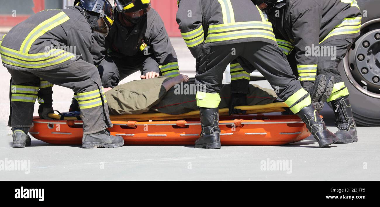 four firefightes and a injured person on the stretcher Stock Photo - Alamy