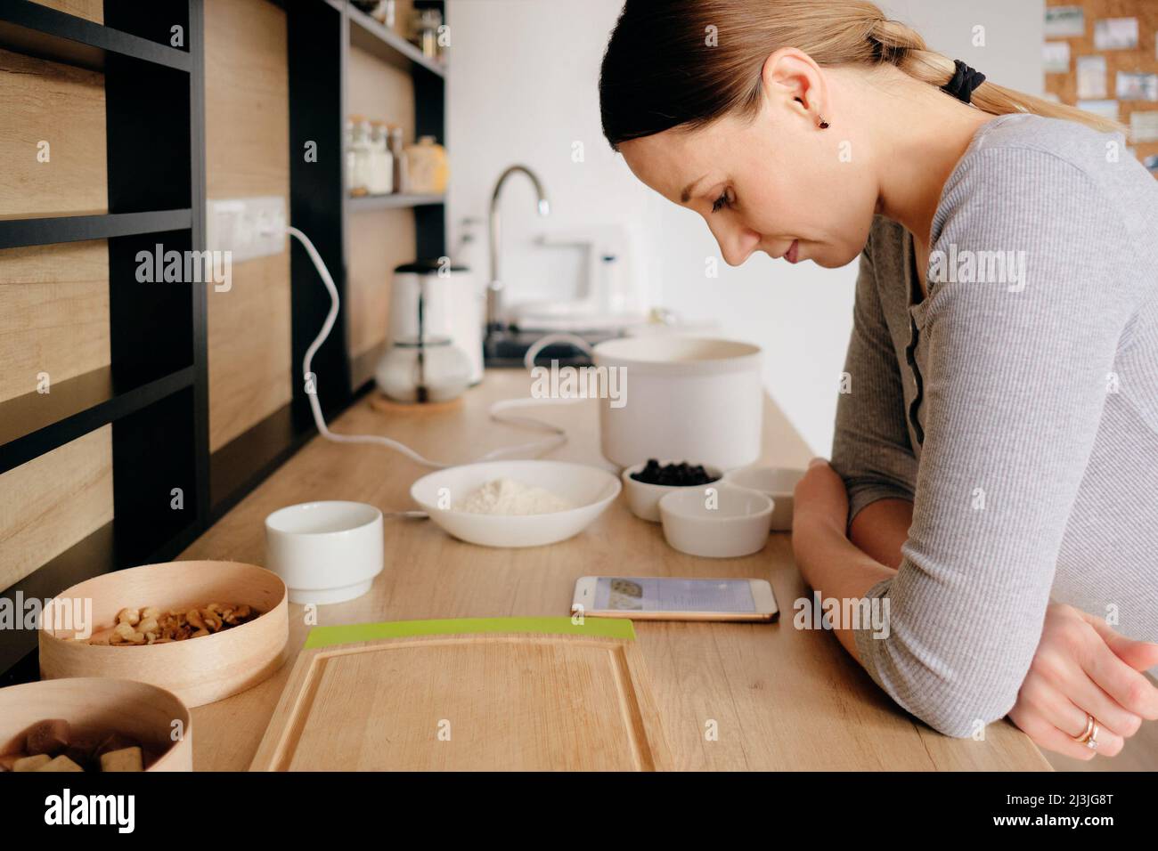 Pretty woman using smartphone, reading recipe online, looking at phone ...