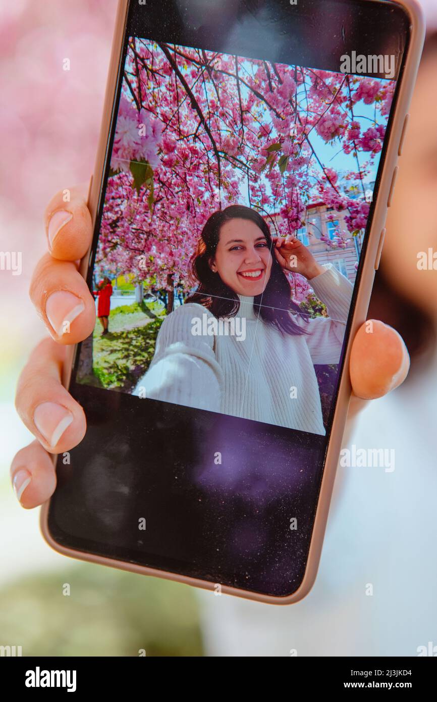 woman shooting her self on the phone under blooming sakura tree selfie ...