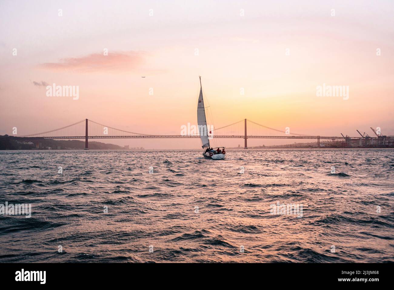 Sailing boat and The 25 de Abril Bridge supension bridge of Lisbon at ...