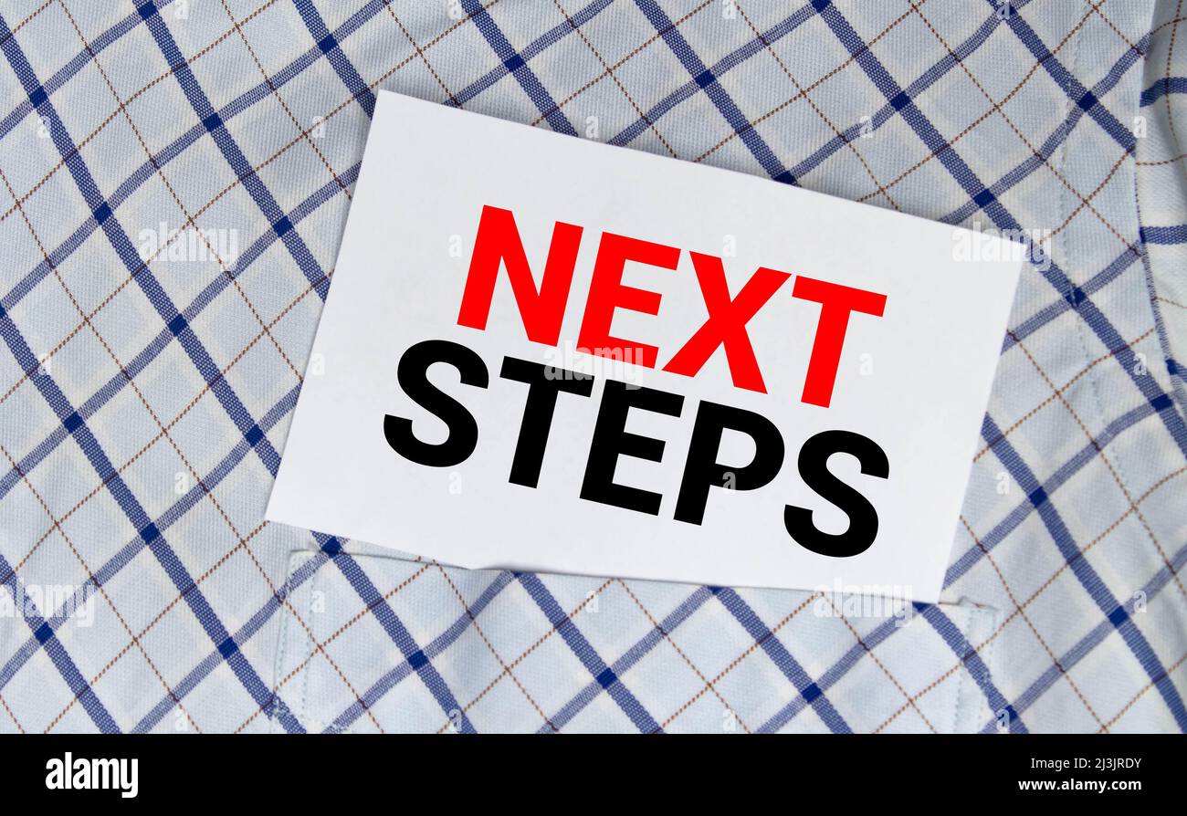 Closeup on businessman holding a card with text NEXT STEPS, business ...