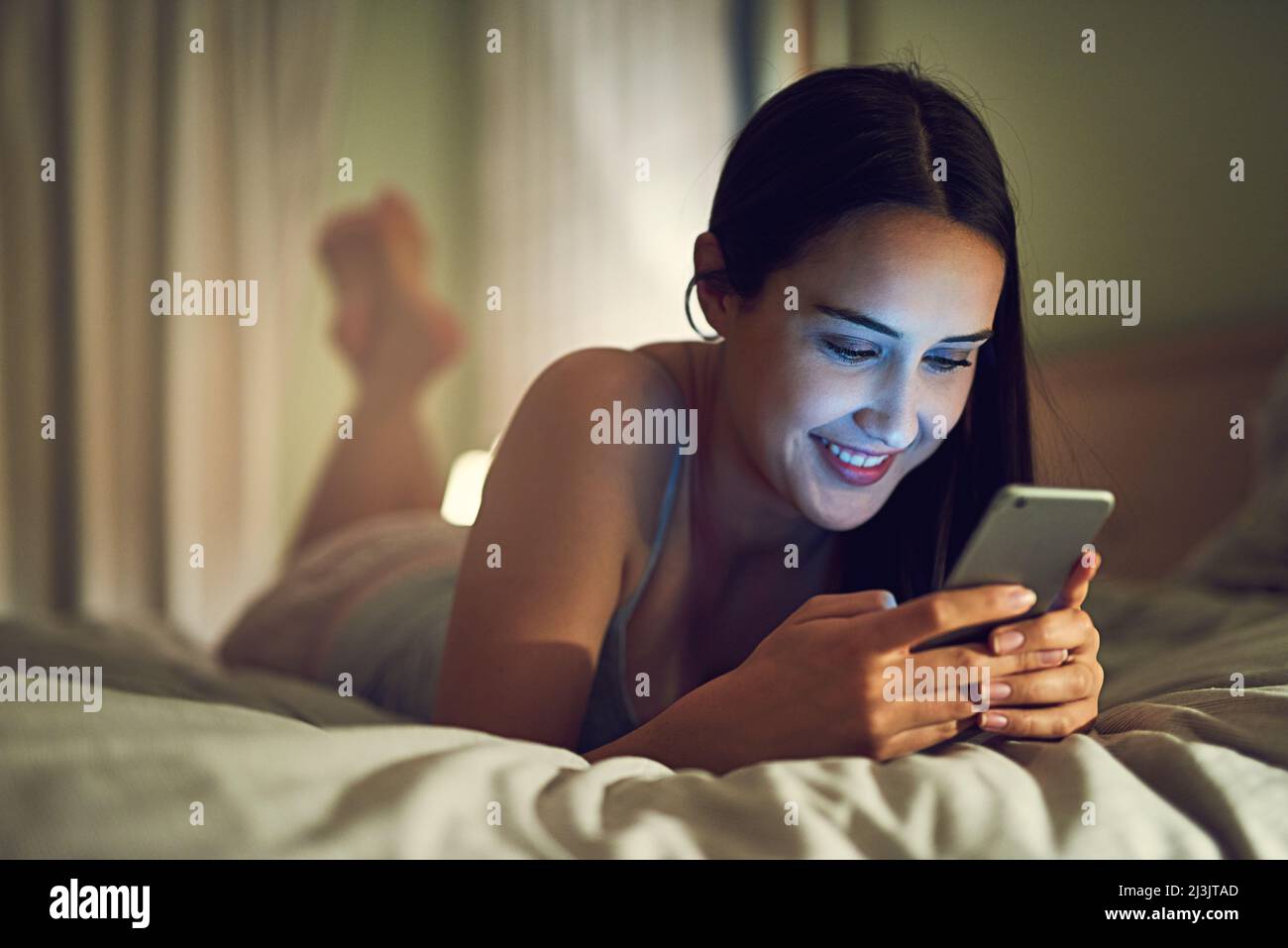 Time for one last message before bedtime. Shot of a young woman using a ...