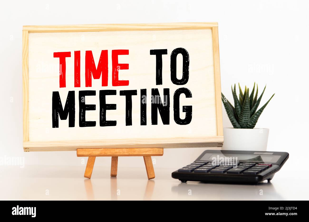 Businessman holding a card with text TIME TO MEETING. Keyboard, diagram ...