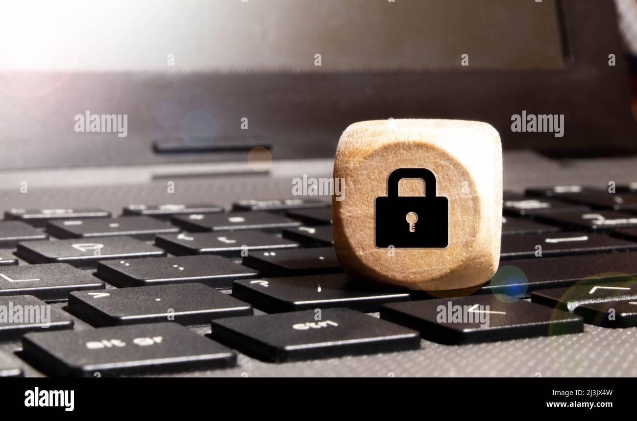 Wooden block with lock graphic on laptop keyboard. Computer security ...