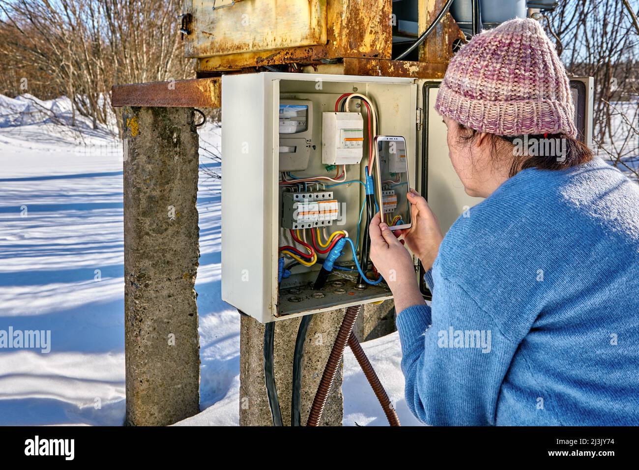 Taking readings from electricity meter using handy by woman in ...