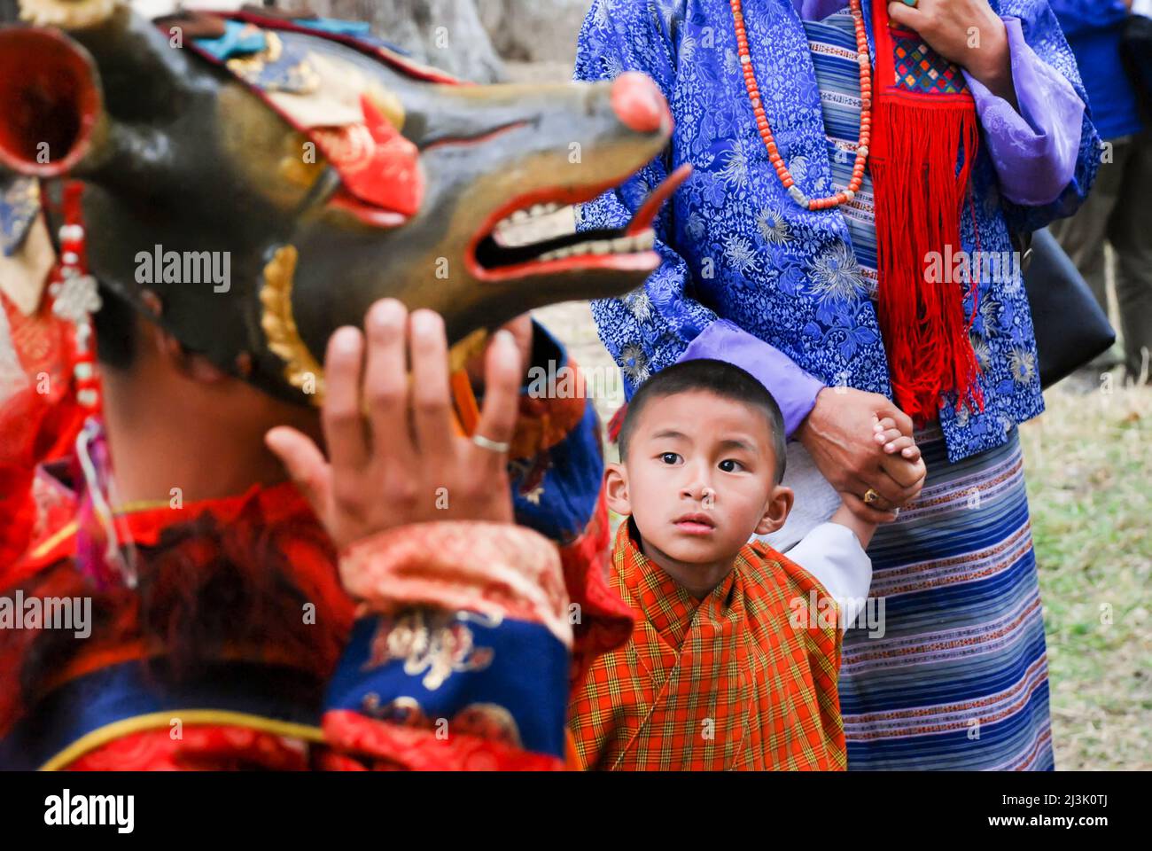 A young boy looks up as a man dons a mask to perform a Cham dance at ...