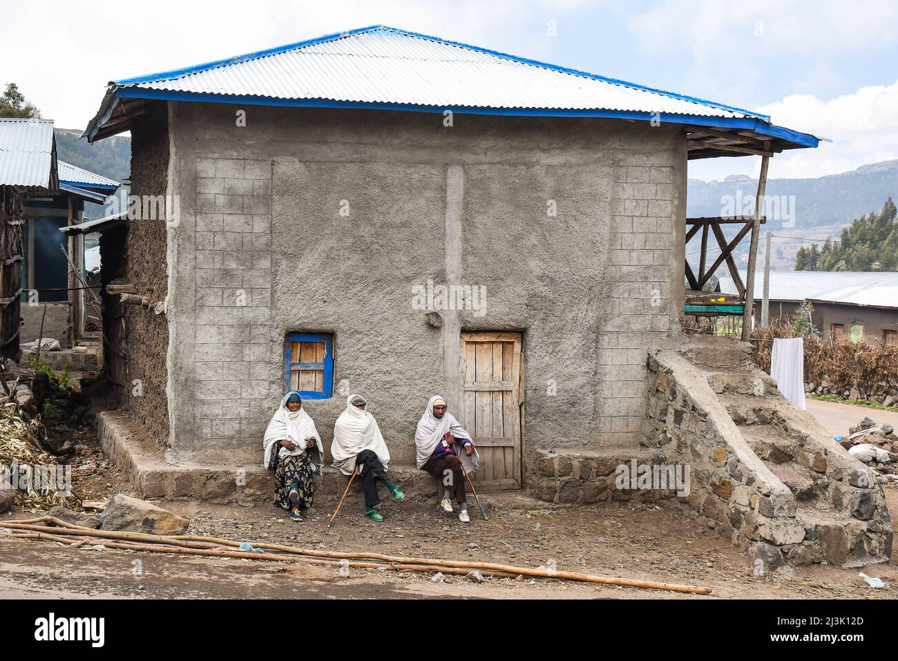 Three people sit outside the doorway of a house in the Highlands of ...