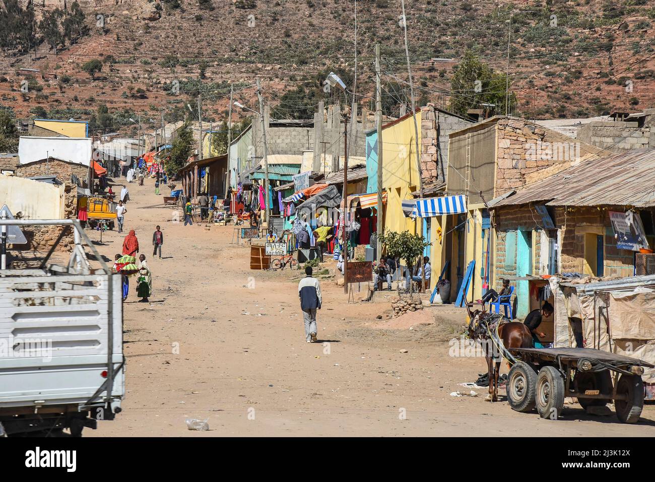 Village in rural Ethiopia and pedestrians on a dirt road lined with ...