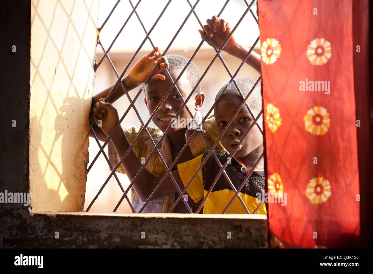 Two young boys peer through a bar window.; Luozi, Democratic Republic ...