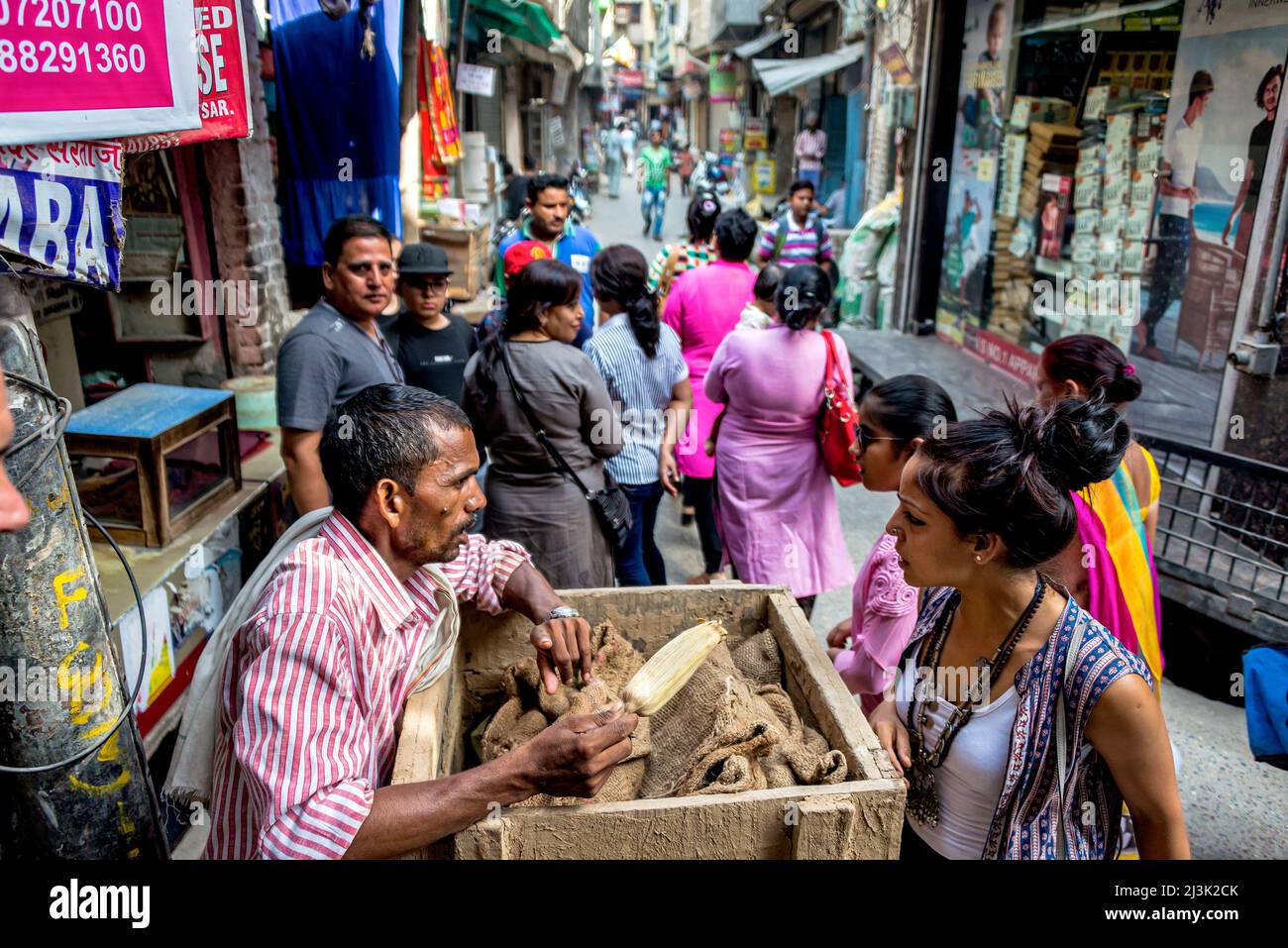 Vendor bartering with shopper, and pedestrians on a street in India ...