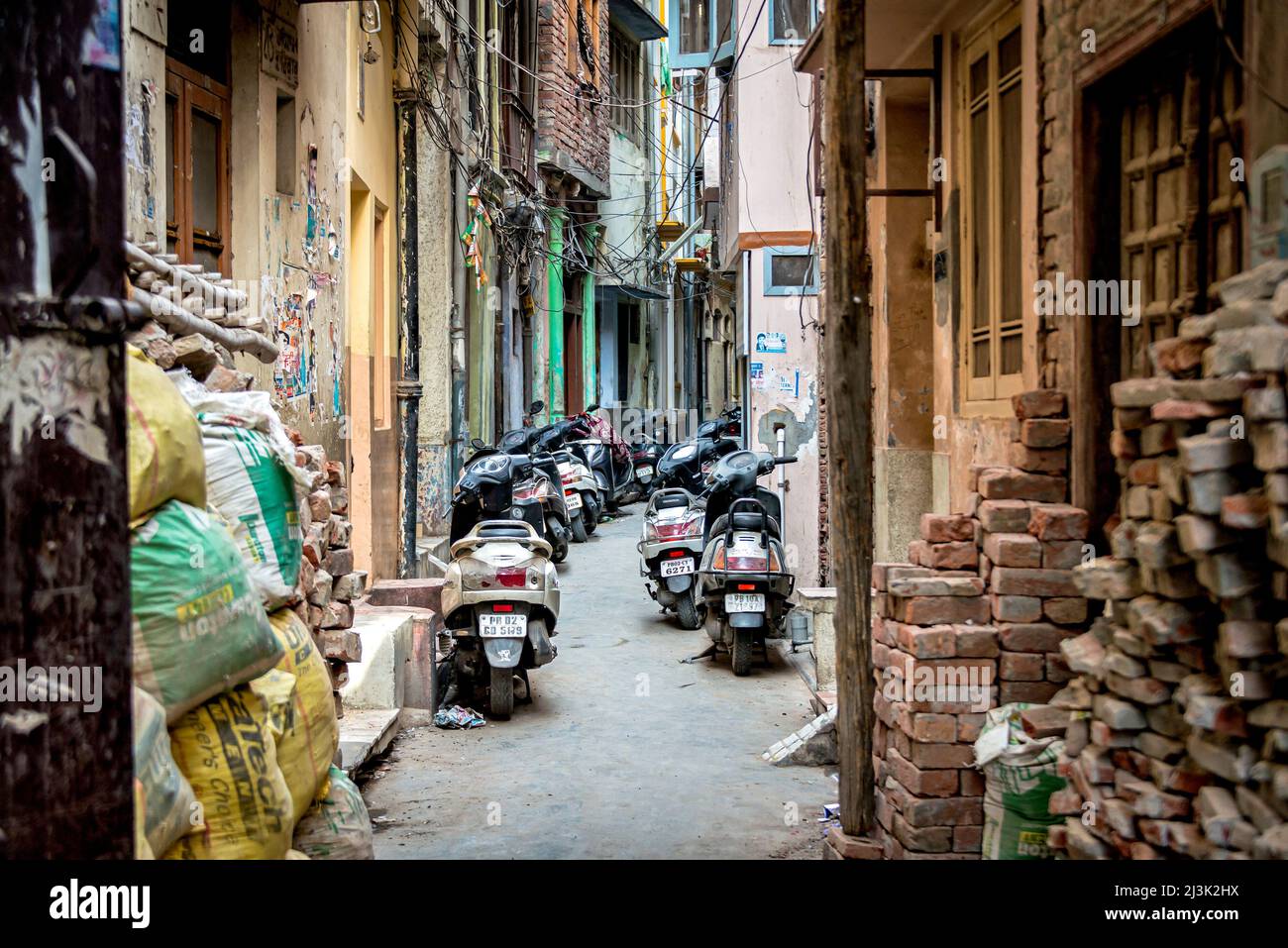 Parked motorcycles line a narrow alley in India; Amritsar, Punjab ...