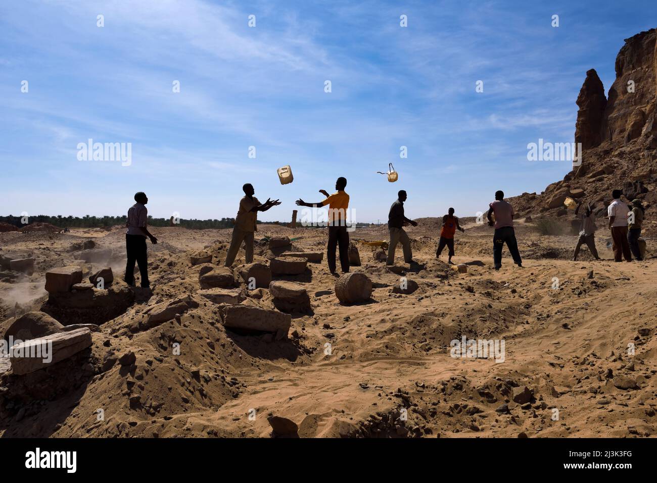 Sudanese workers throw buckets to each other in an efficient way of ...