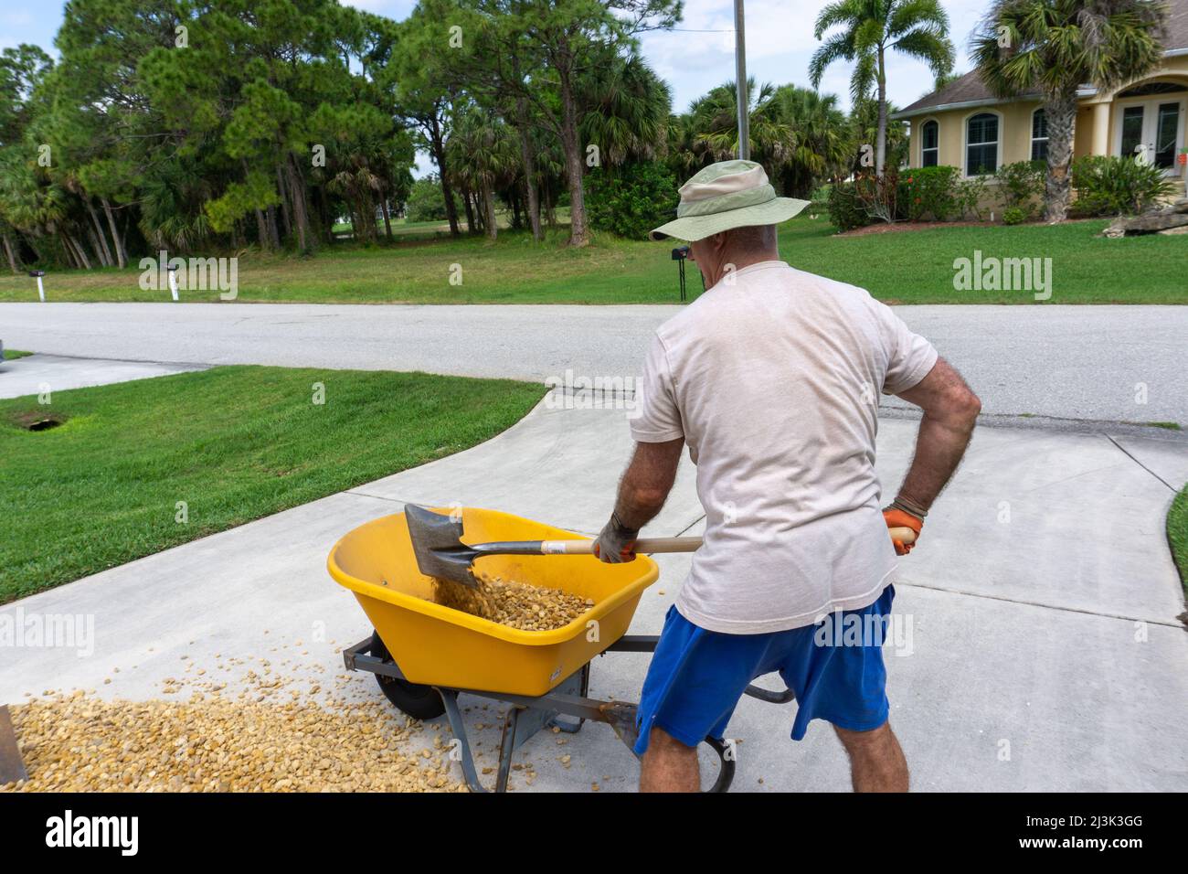 Man pours rocks into wheelbarrow with shovel Stock Photo - Alamy