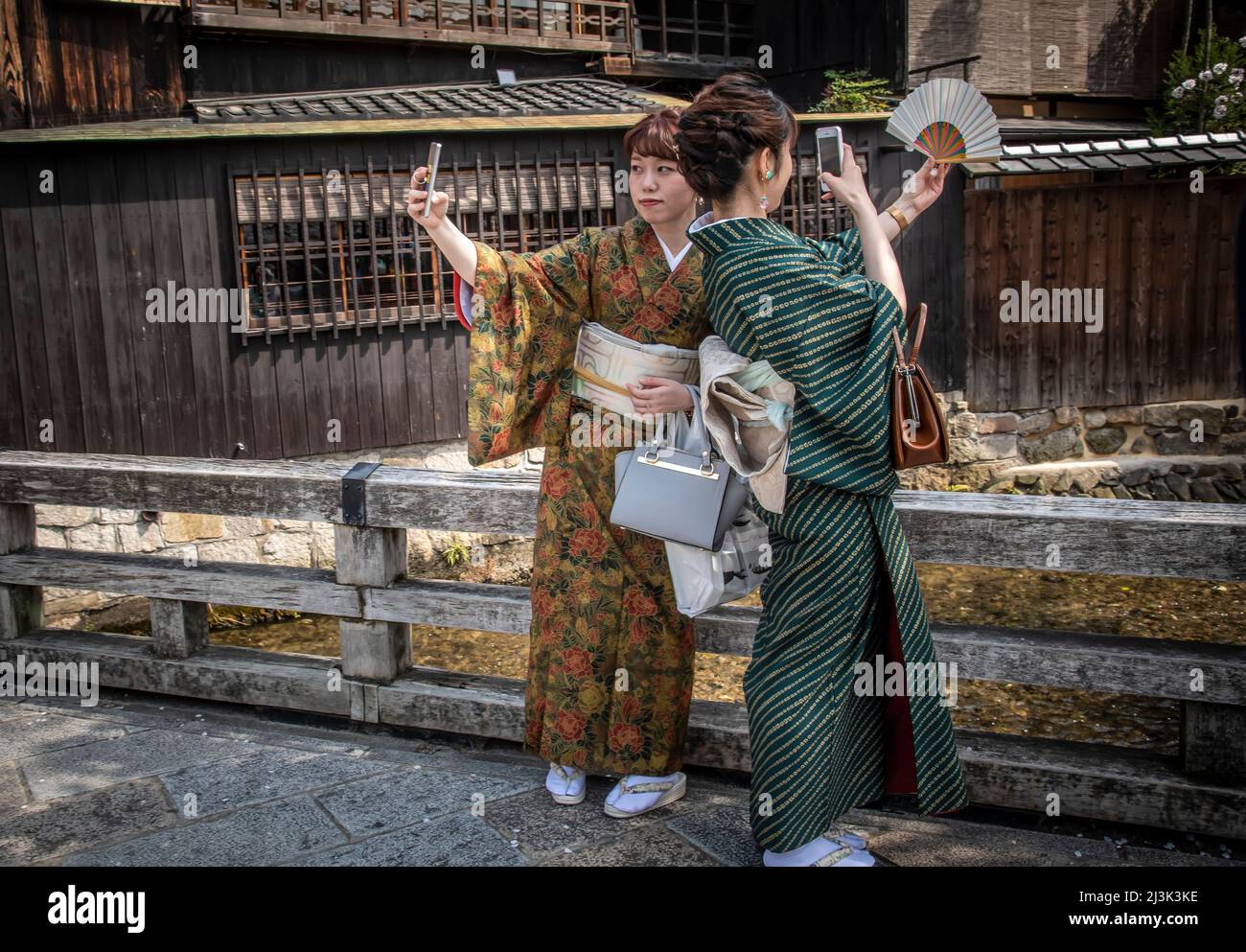 Women wearing traditional dress taking pictures in the Gion area of ...