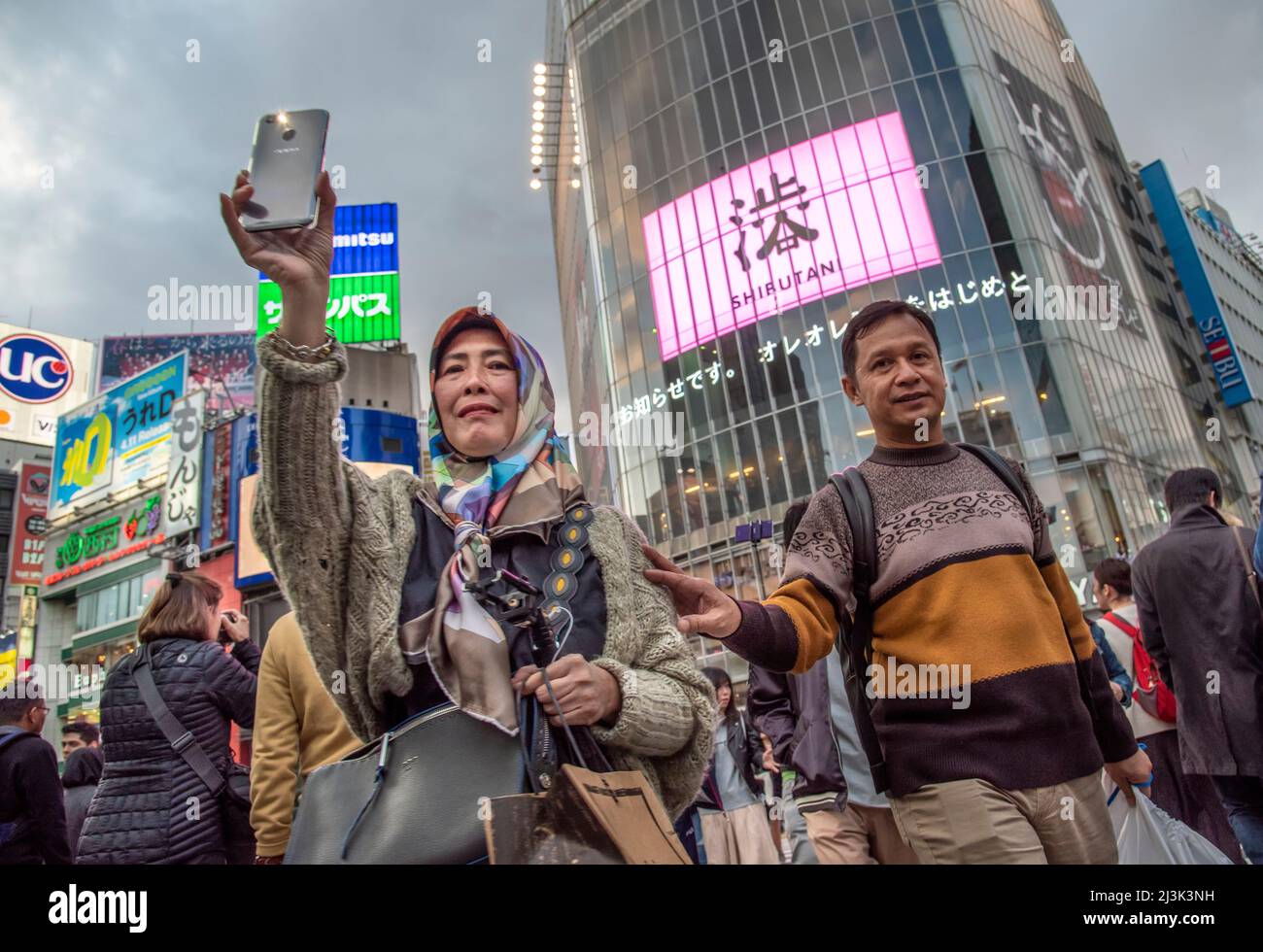 Shopper in downtown Tokyo taking a cell phone picture in the midst of a ...
