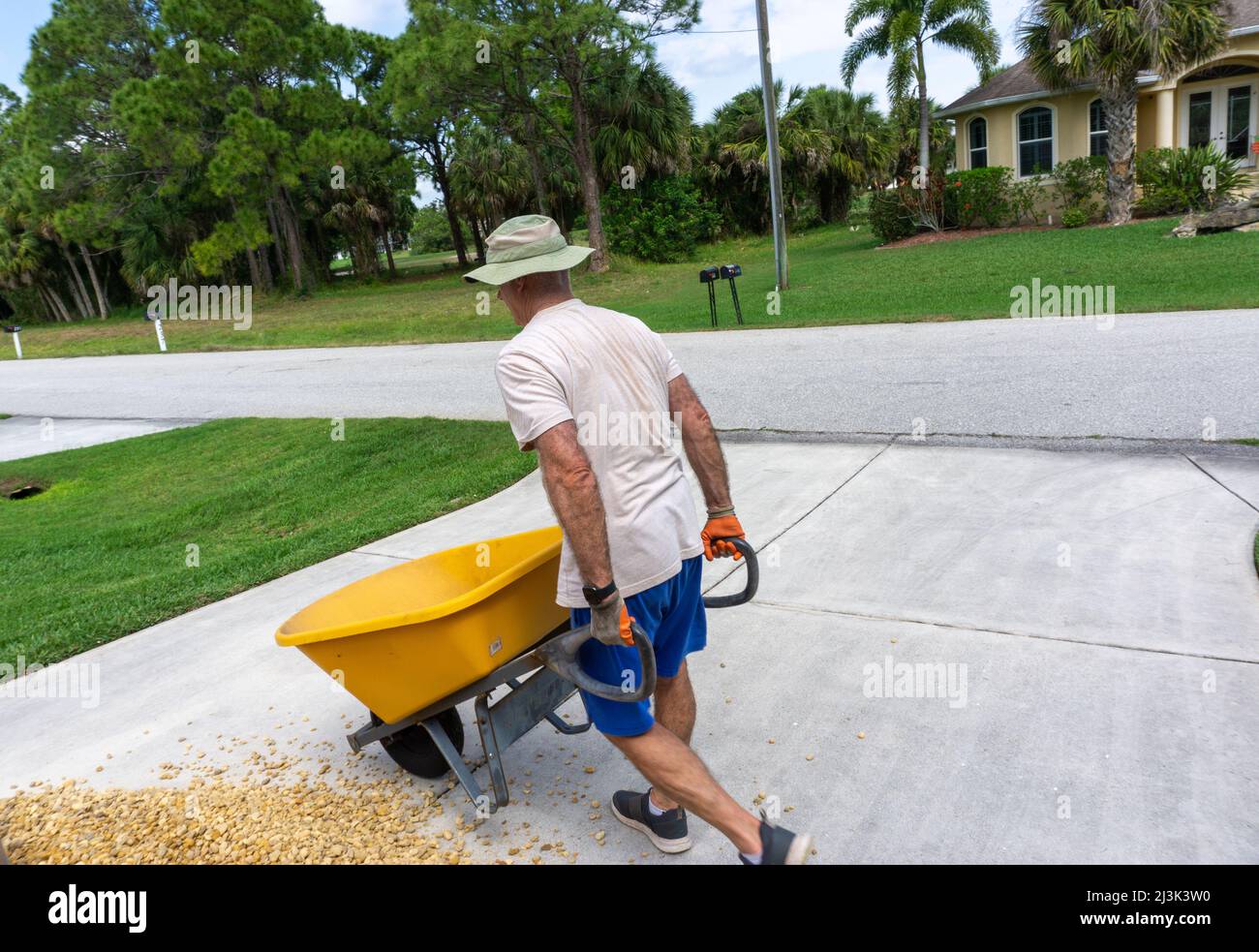 Man walking with full wheelbarrow Stock Photo - Alamy