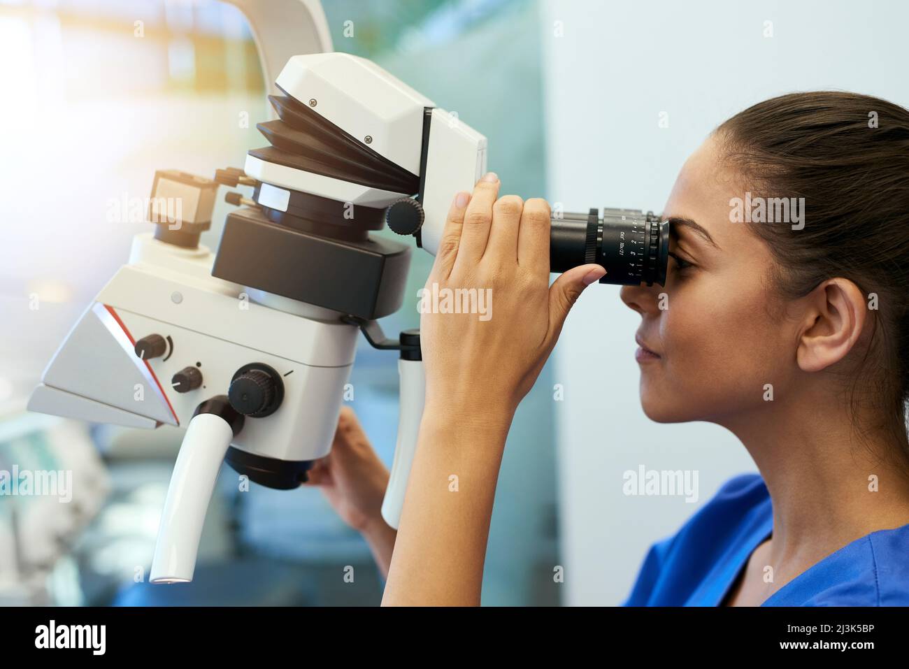 Taking a closer look. Shot of a young pathologist looking at samples ...