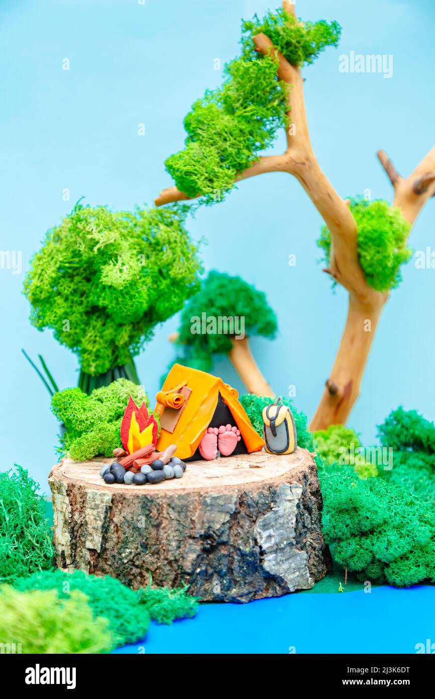 Tourist camp. Plasticine landscape with a tent, a campfire and a ...