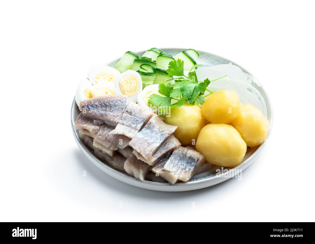Salted herring with boiled potatoes and quial eggs on a white plate ...