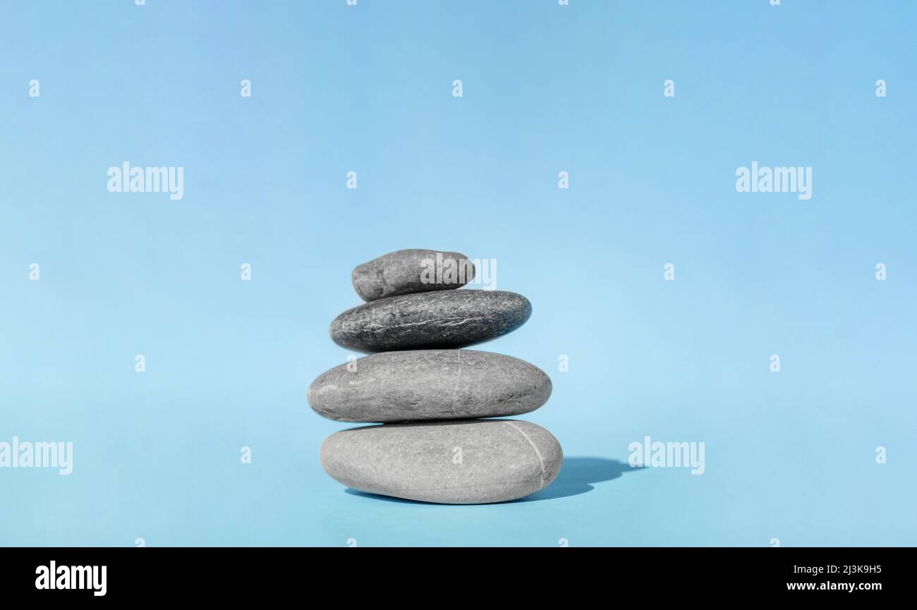Balanced pebble stones for spa treatments on blue background. The ...