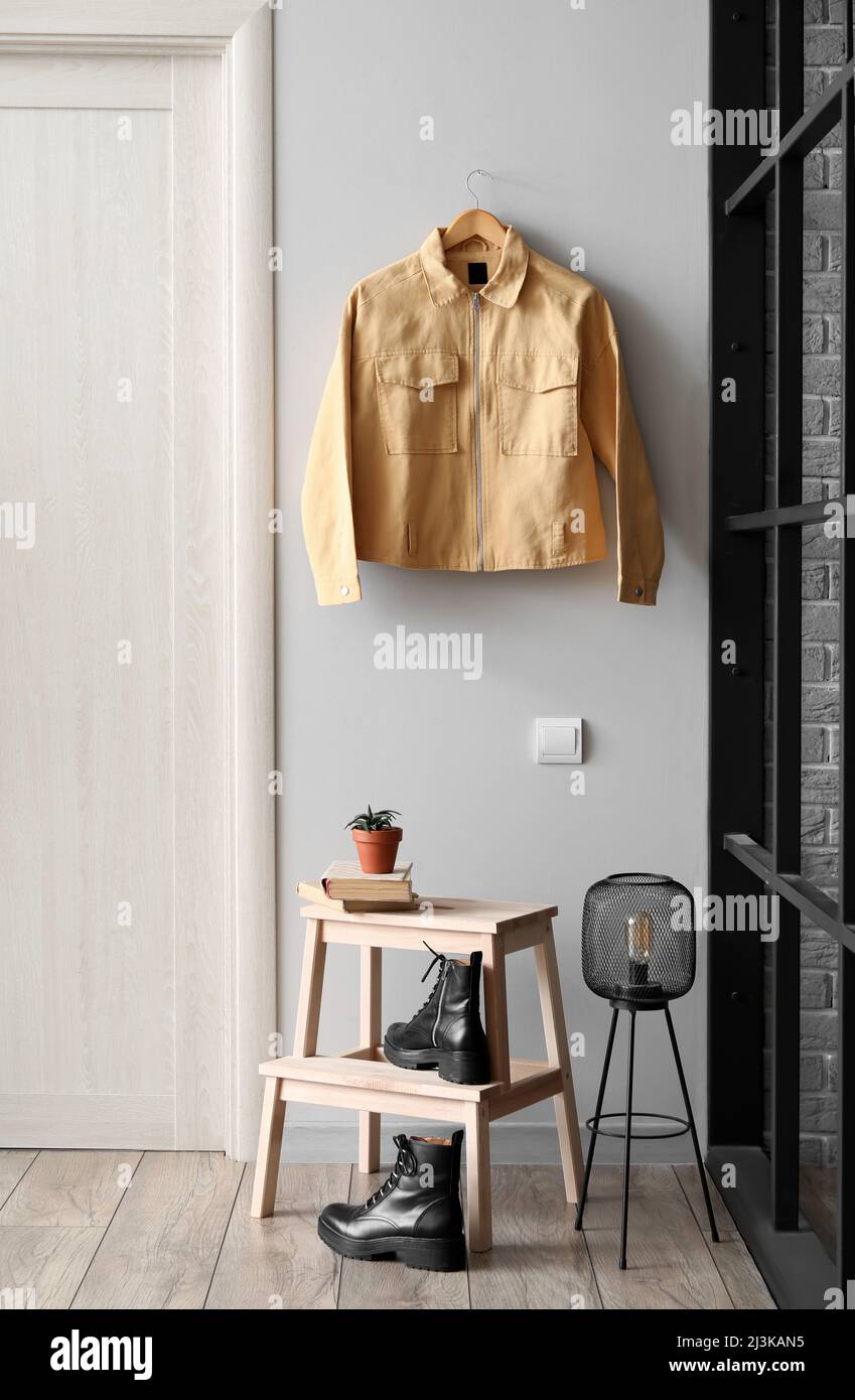 Stepladder stool with shoes and jacket hanging on light wall in hallway ...