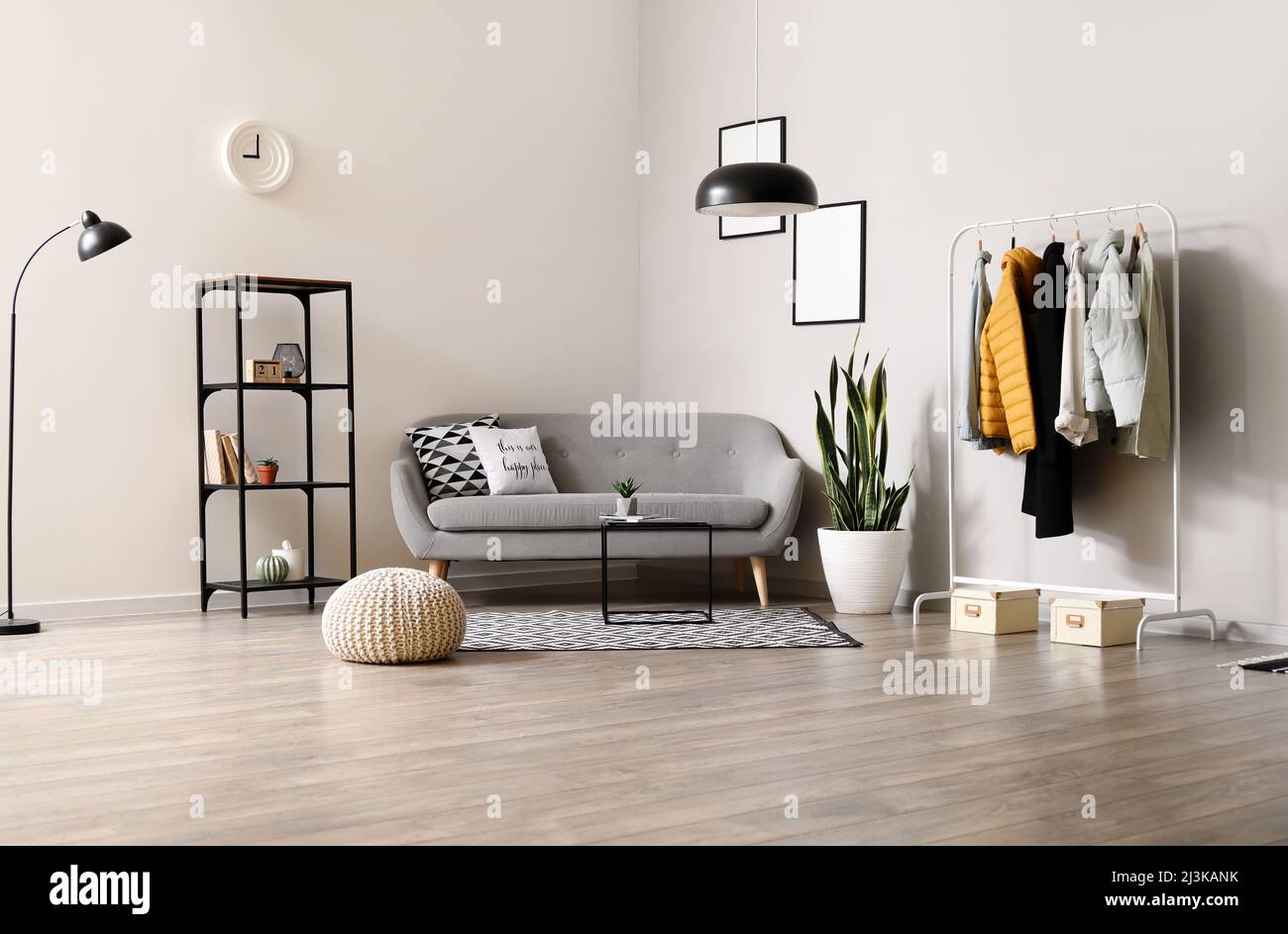 Interior of light room with sofa and hanger with jackets Stock Photo ...