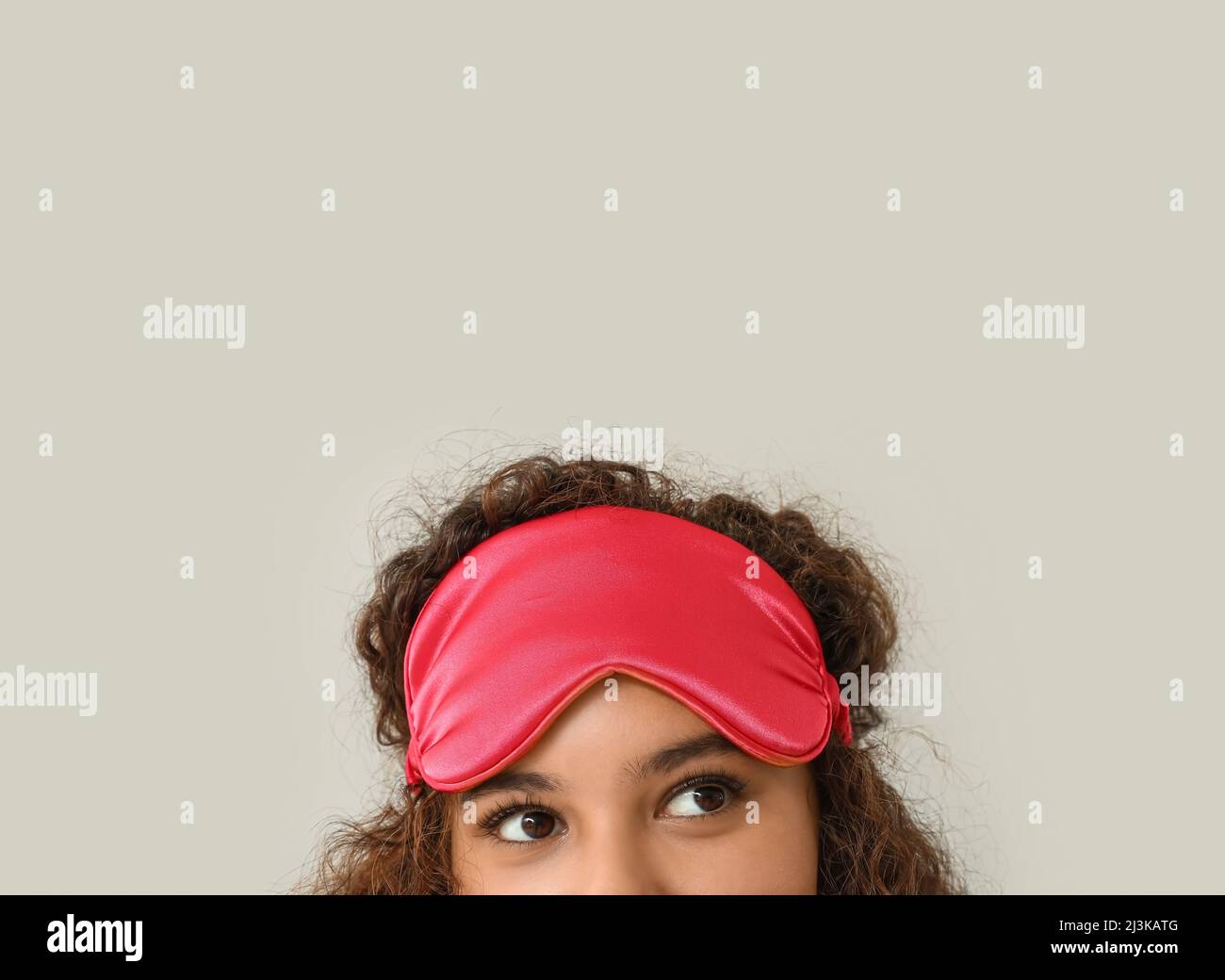 Young African-American woman with red sleeping mask on grey background ...
