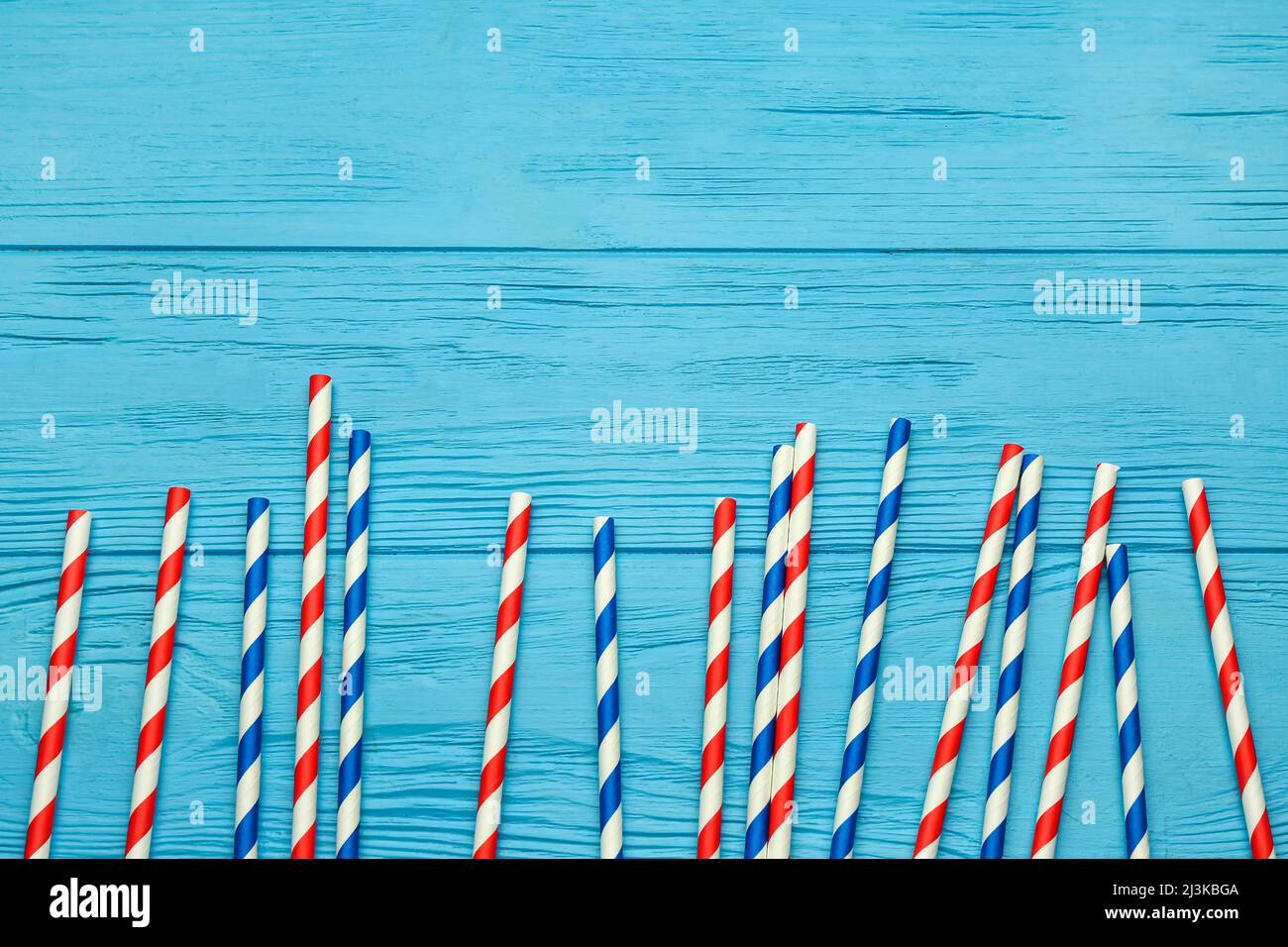 Stylish straws for drinks on blue wooden background Stock Photo - Alamy