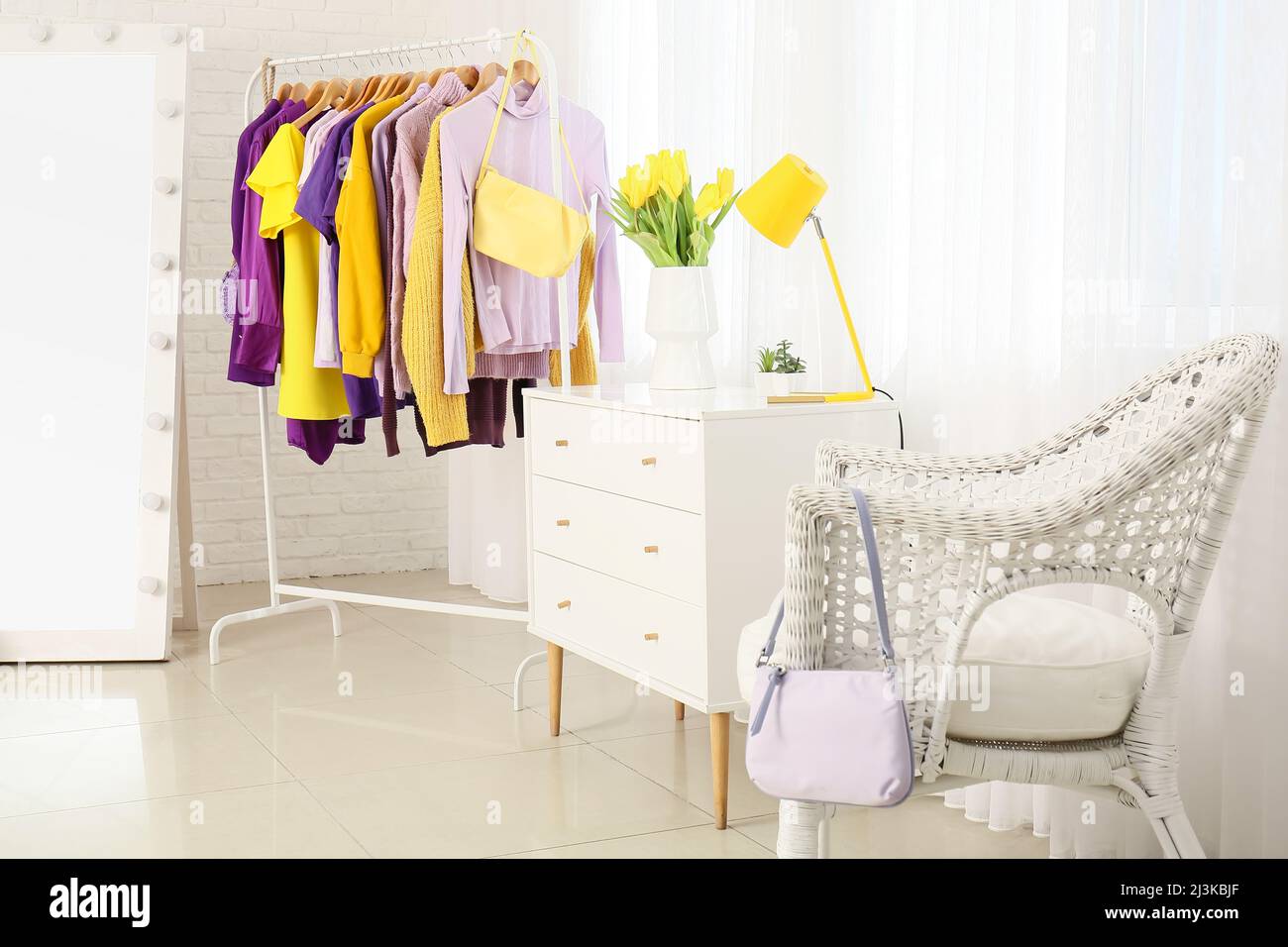 Interior of light dressing room with clothes, commode and armchair ...