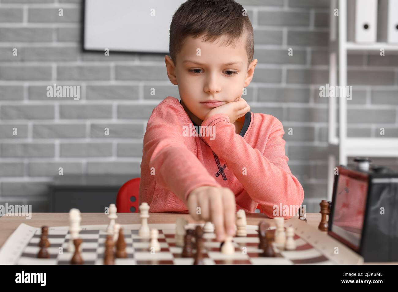 Little boy playing chess during tournament in club Stock Photo - Alamy