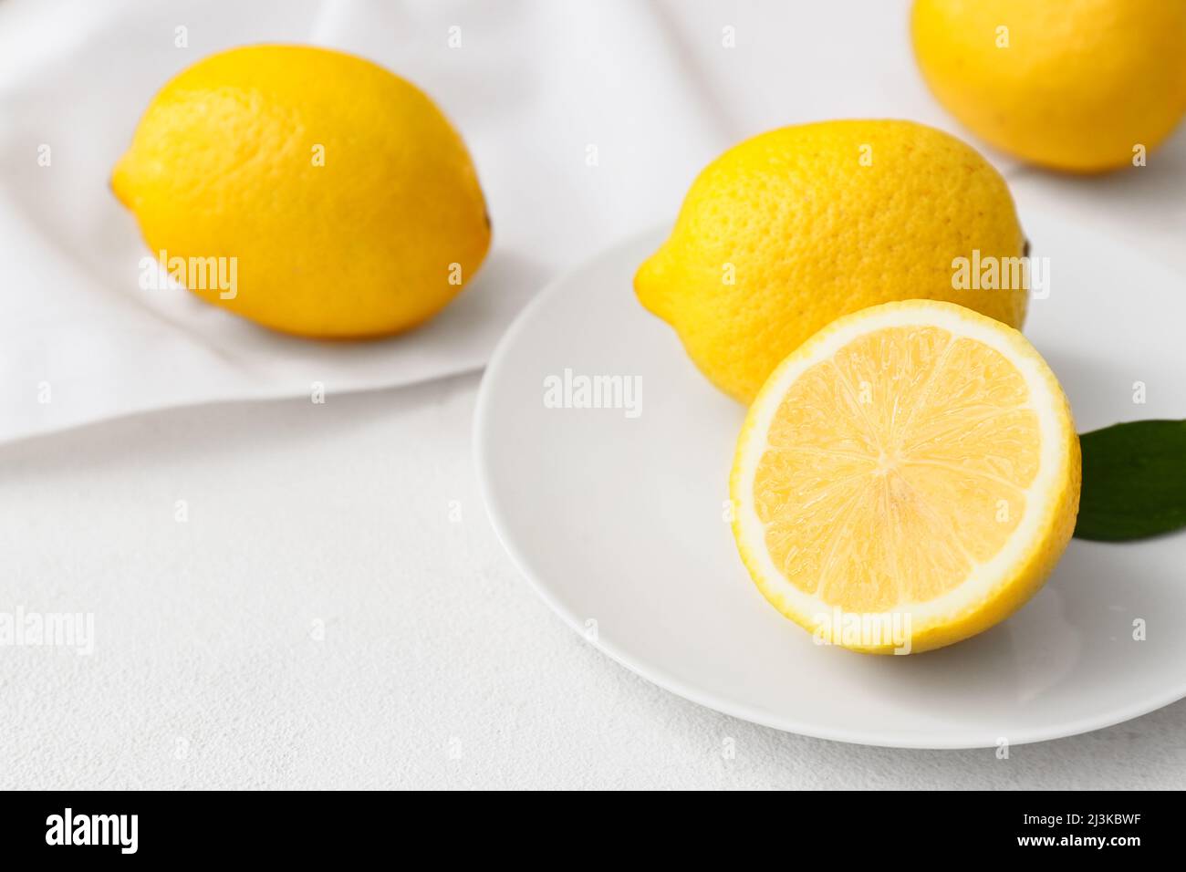 Plate with fresh lemons on light table Stock Photo - Alamy