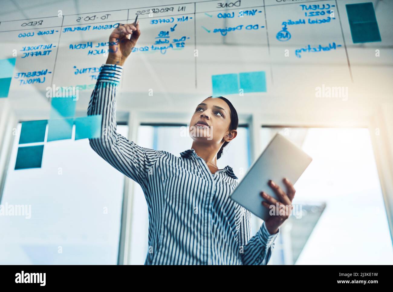 Mapping out the route to her goals. Shot of a young businesswoman using ...