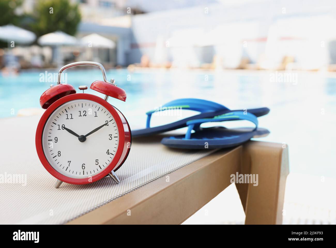 Flip flops alarm clock on deck chair by pool Stock Photo - Alamy