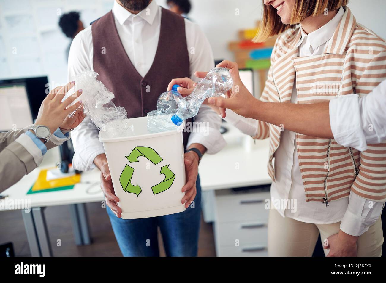 Environmentally focused employees recycling together in the office ...