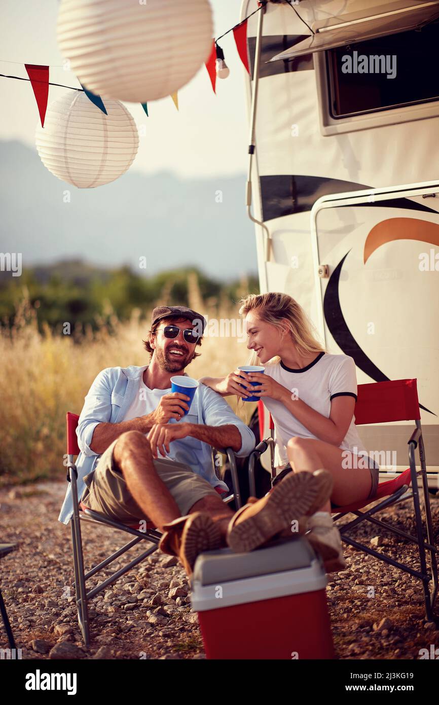 Couple in front of camper rv having small talk and laughing. Roadtrip ...