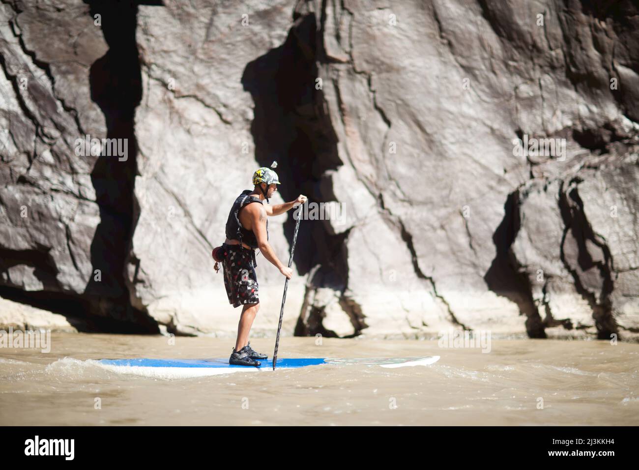 A man surfs on his stand up paddleboard on the Colorado River in a ...