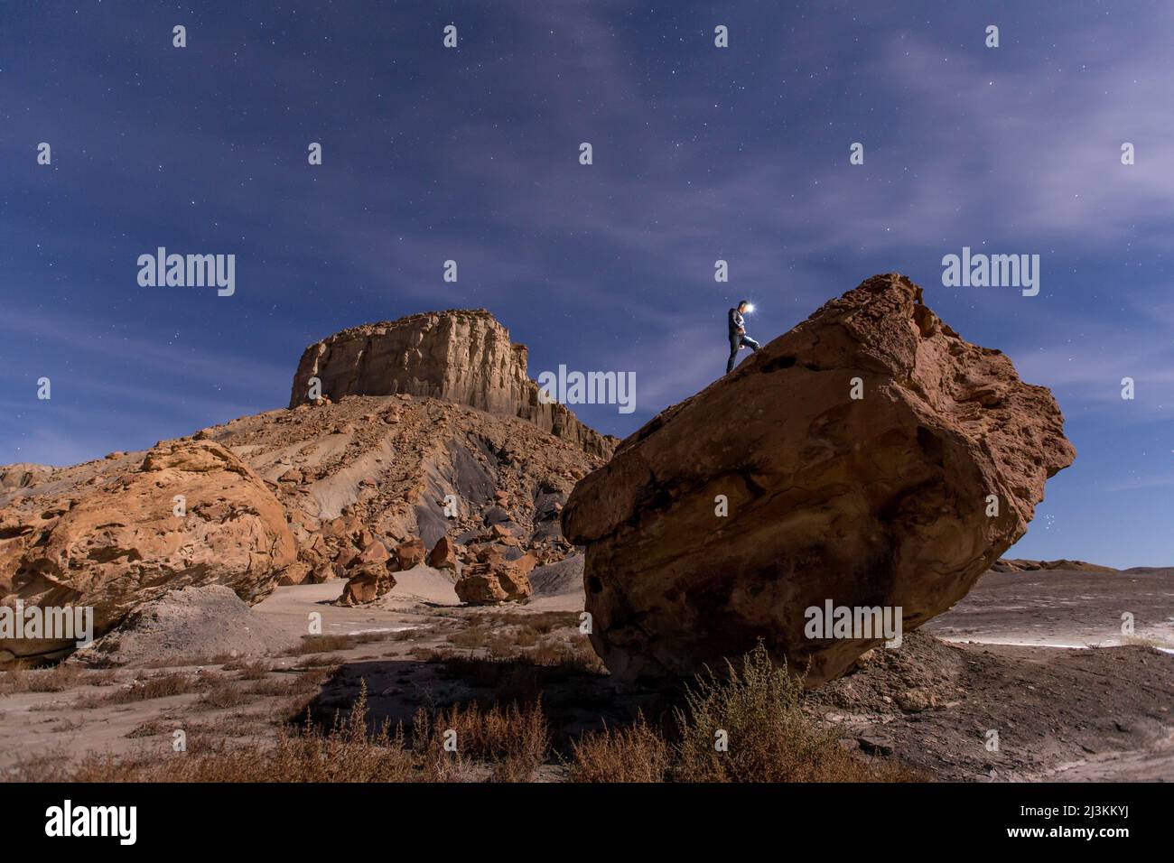 A man on top of a boulder under the nights sky in the desert Stock ...
