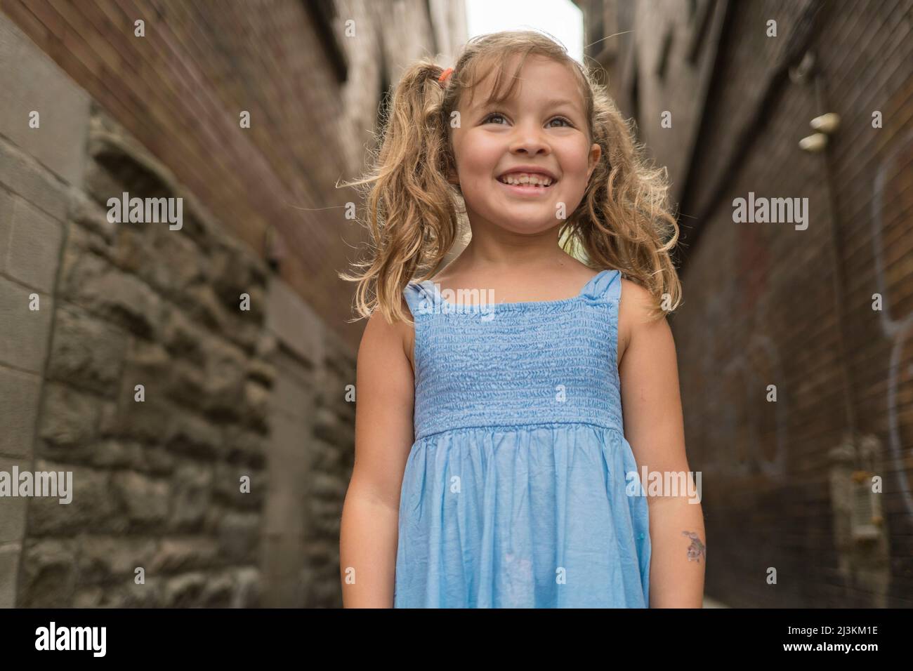 Outdoor portrait of a young girl standing in an alley; Toronto, Ontario ...