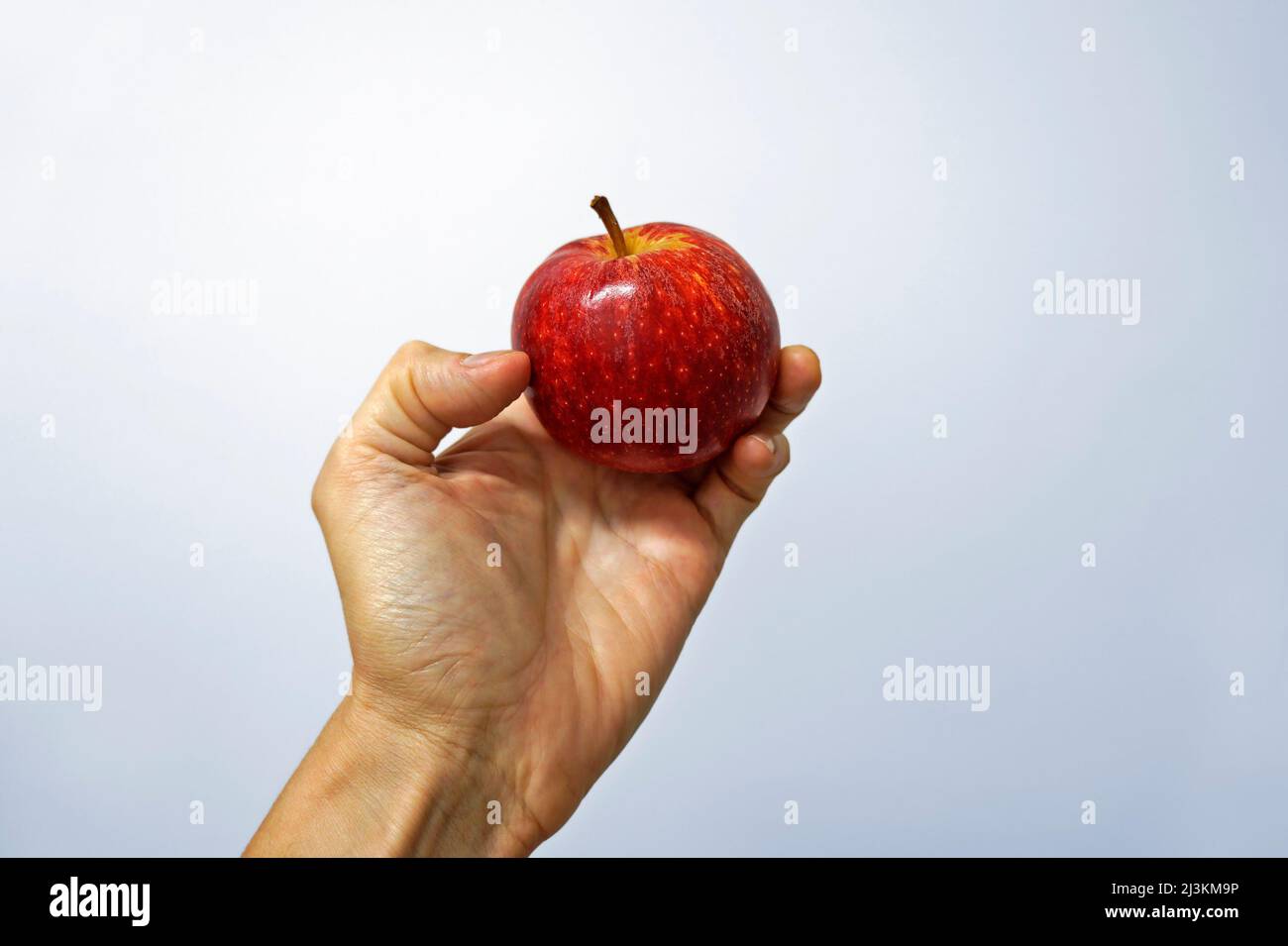 Red apple on hand in a bright background Stock Photo - Alamy