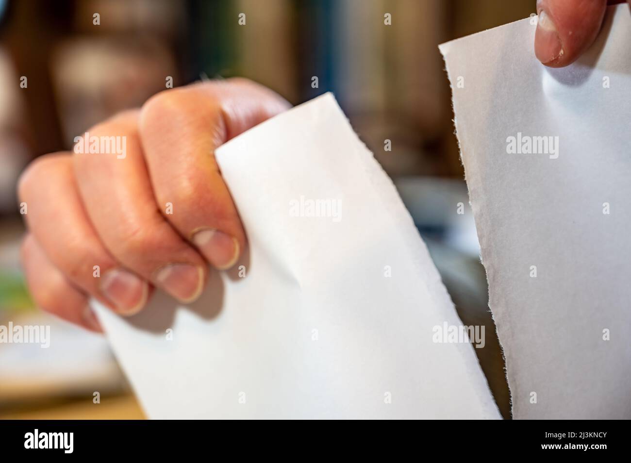 Two hands tearing a single blank sheet of paper from top to bottom ...