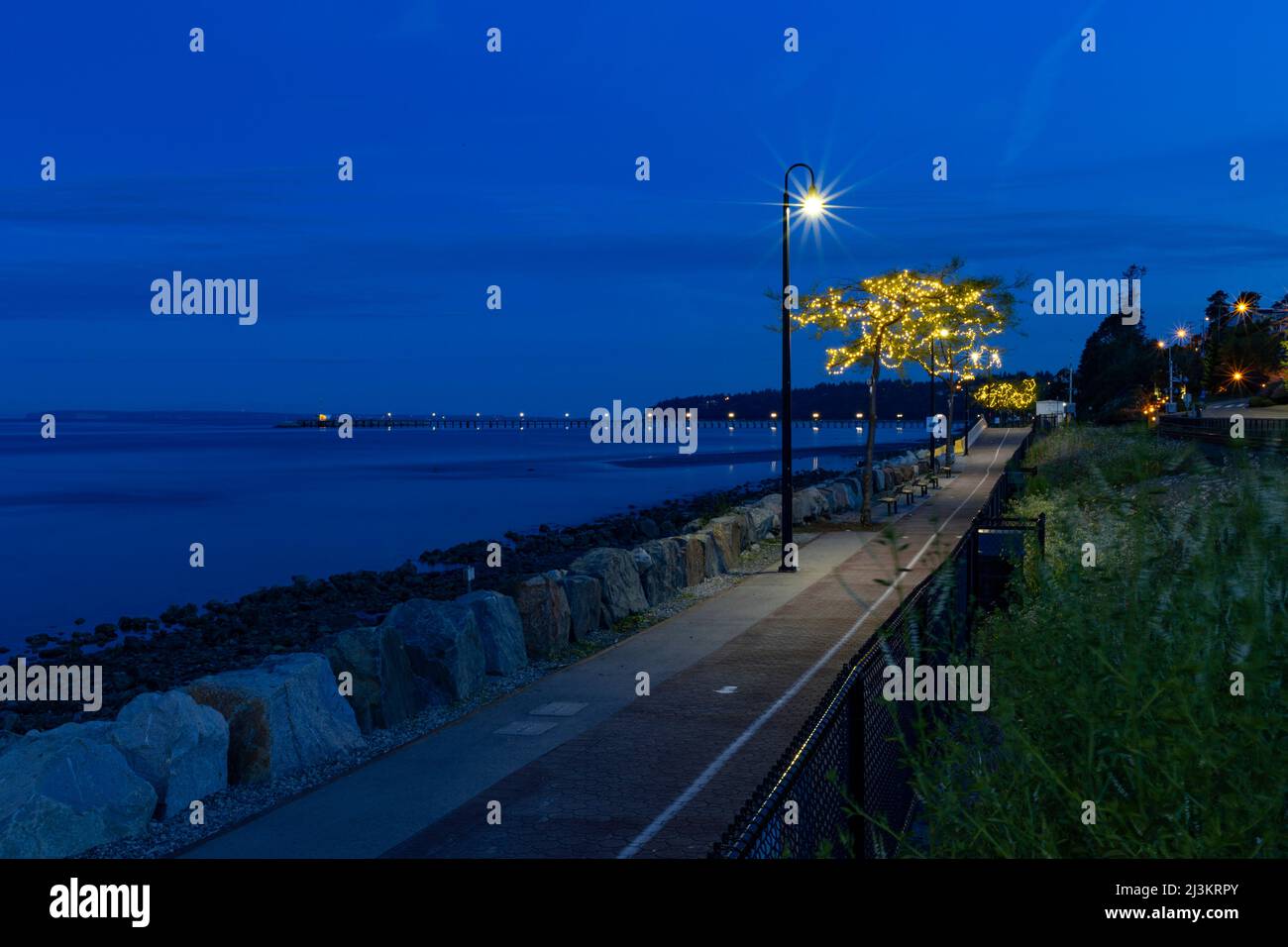 Light illuminated along an ocean promenade in early morning before ...
