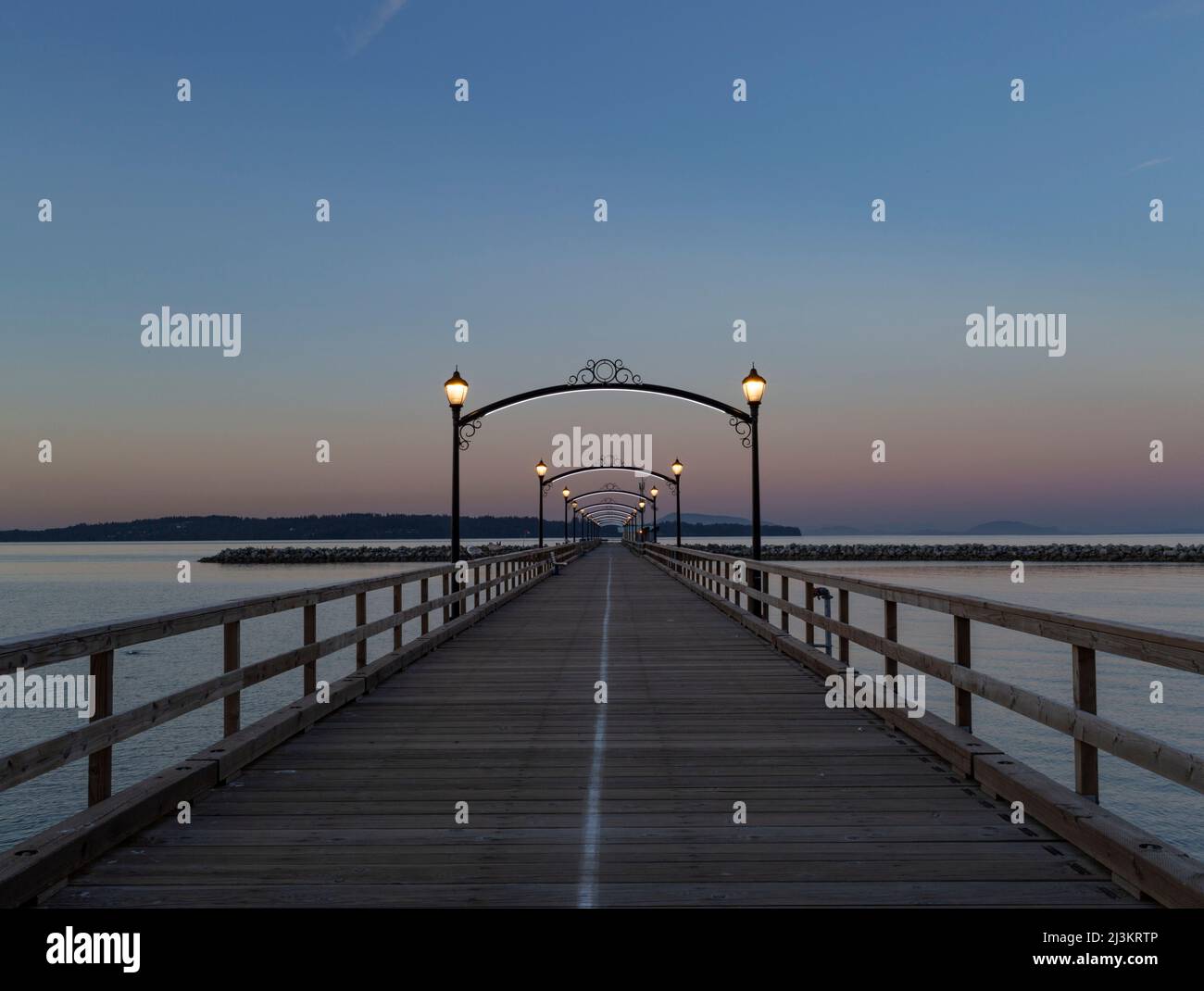 Lights illuminated along the White Rock pier at sunrise in BC, Canada ...